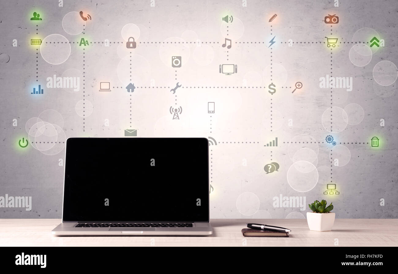 Laptop on office desk with media icons Stock Photo - Alamy