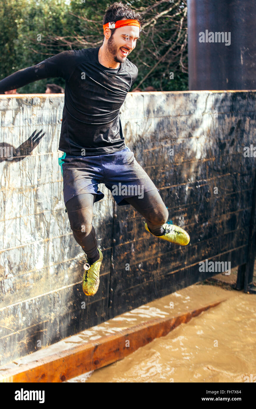 Participant in extreme obstacle race jumping over wall Stock Photo - Alamy
