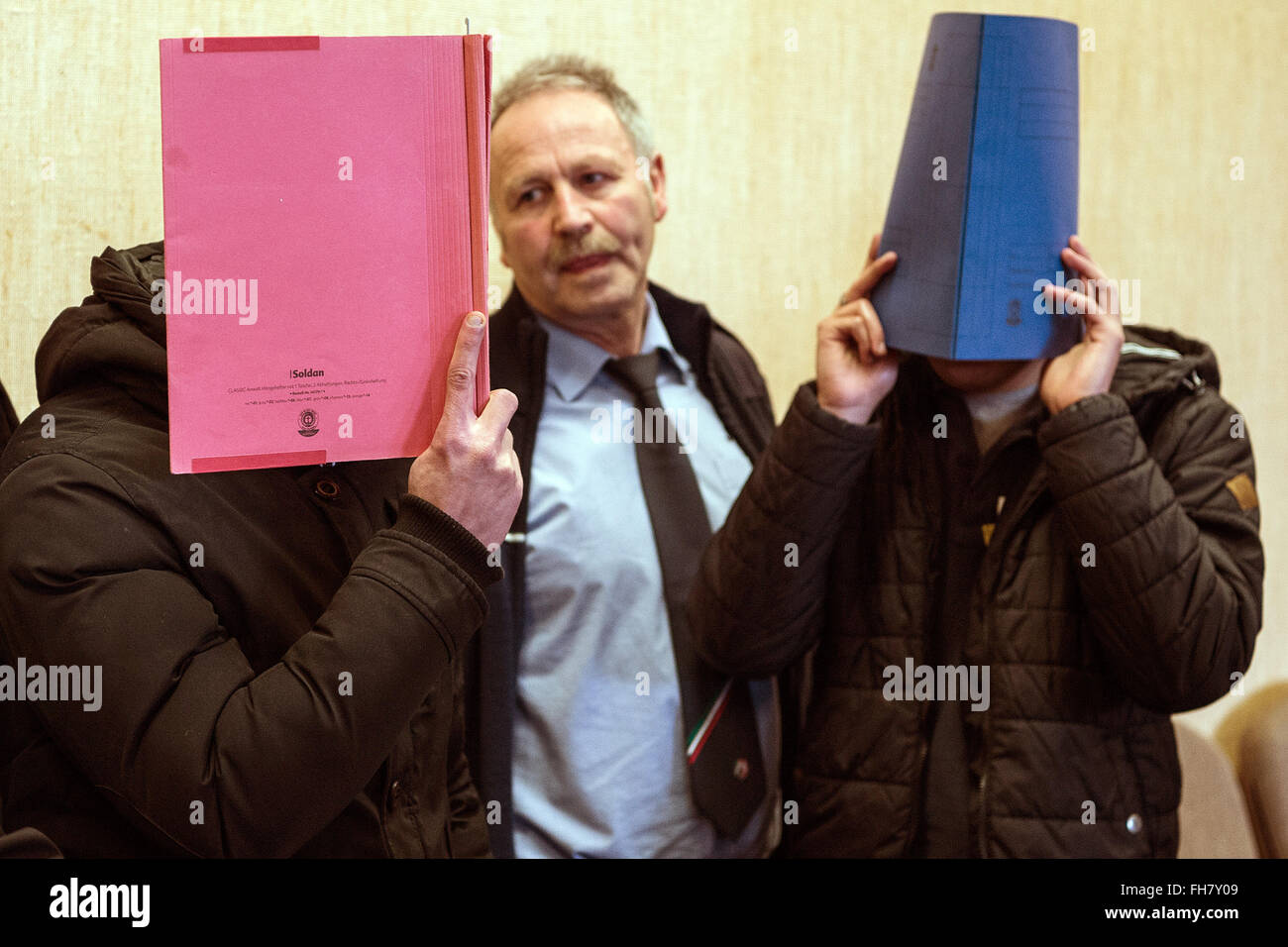 Two defendants hold file folders in front their faces in the courtroom ... Two defendants hold file folders in front their faces in the courtroom ...