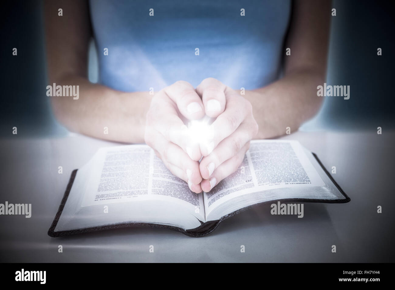 Composite image of woman praying while reading bible Stock Photo - Alamy