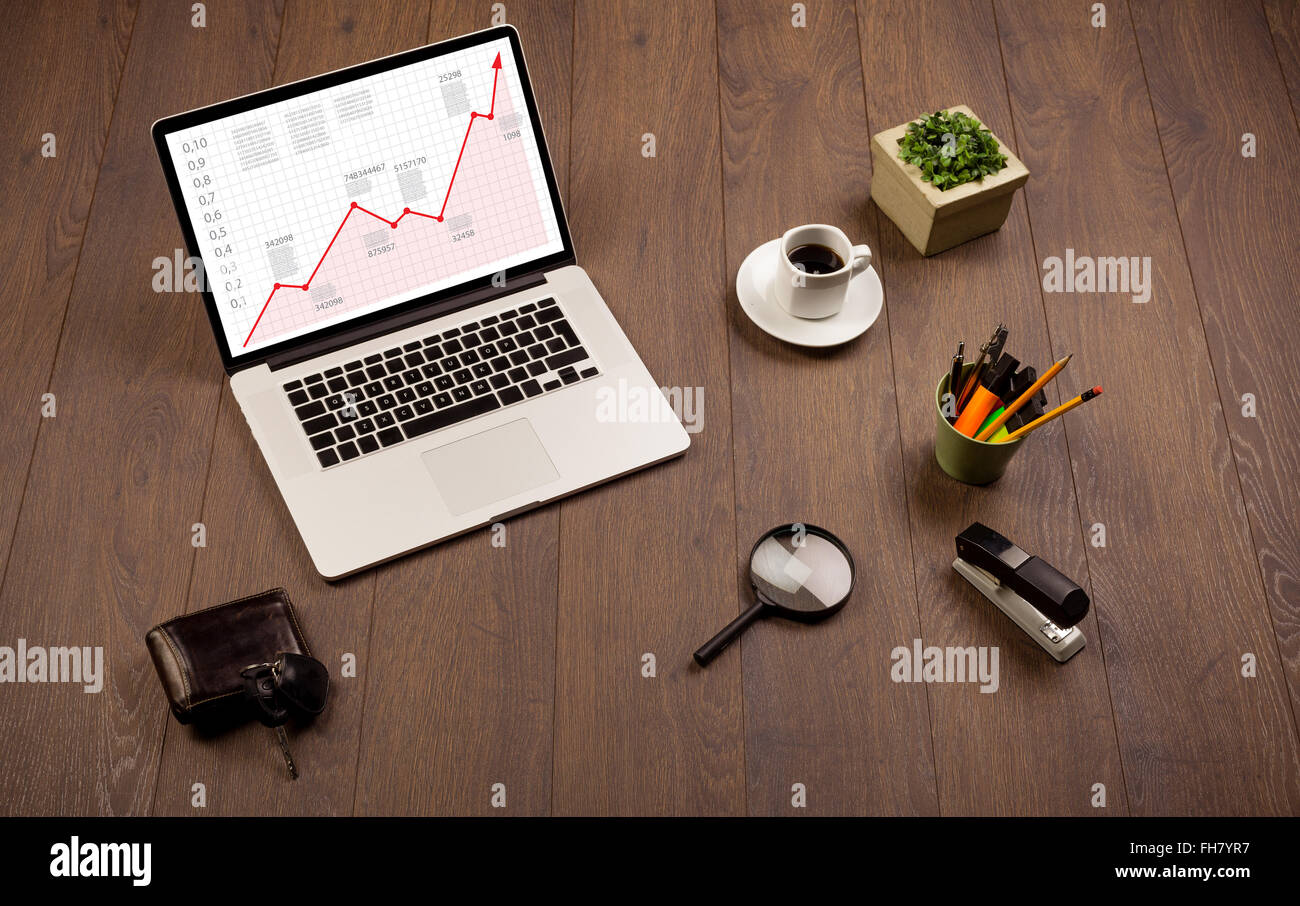 Computer desk with laptop and red arrow chart in screen Stock Photo - Alamy