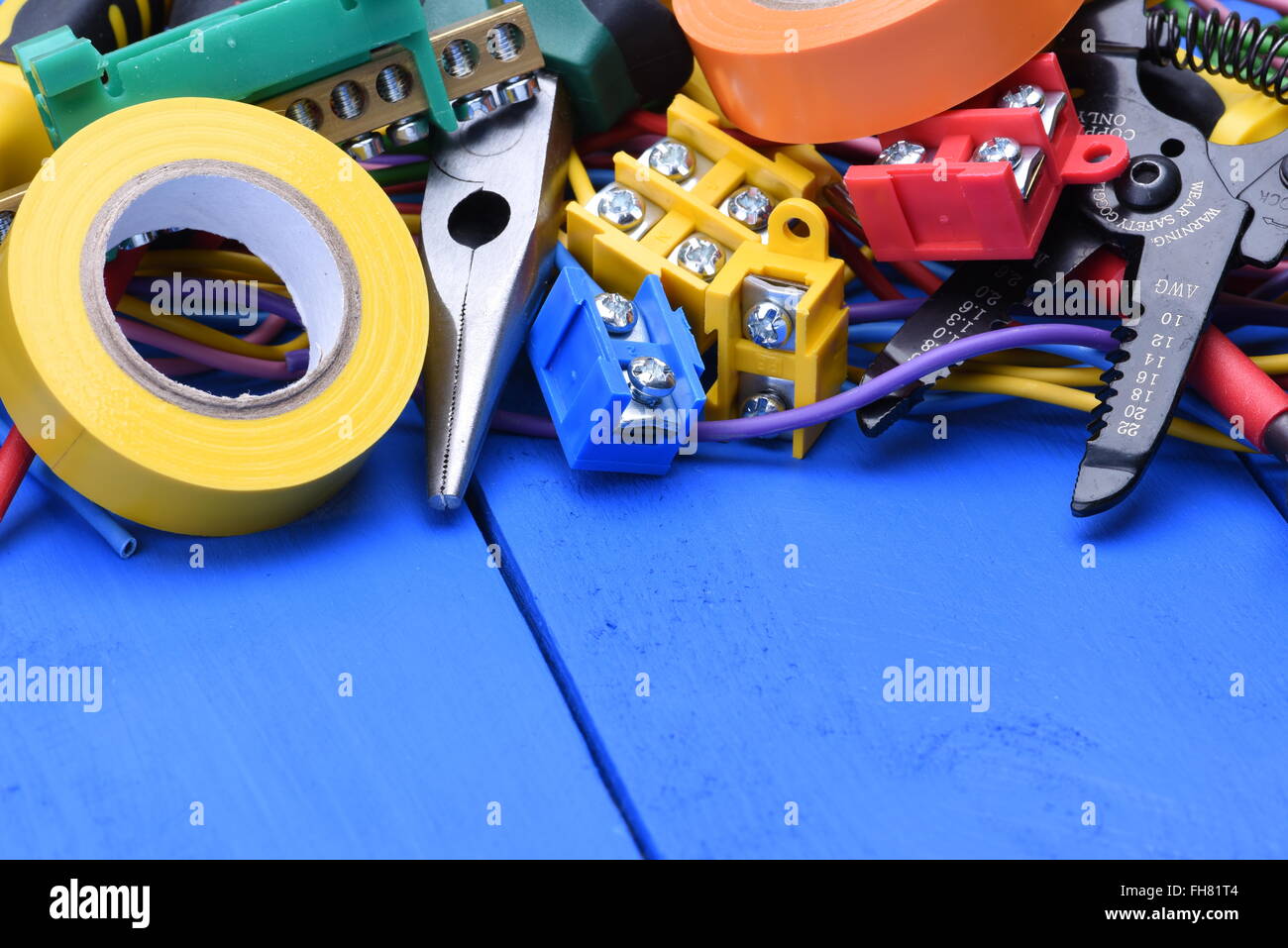 Tools and component kit used in electrical installations on blue wooden ...