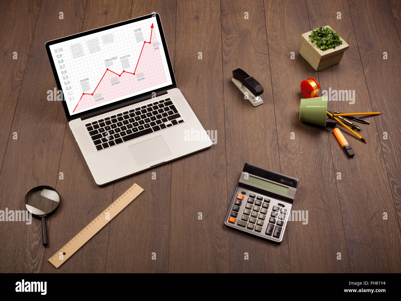 Computer desk with laptop and red arrow chart in screen Stock Photo - Alamy
