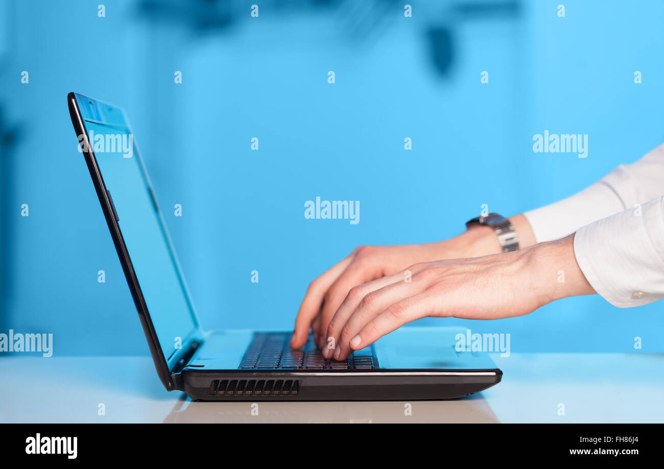 Businessman pressing modern laptop computer on colorful background ...