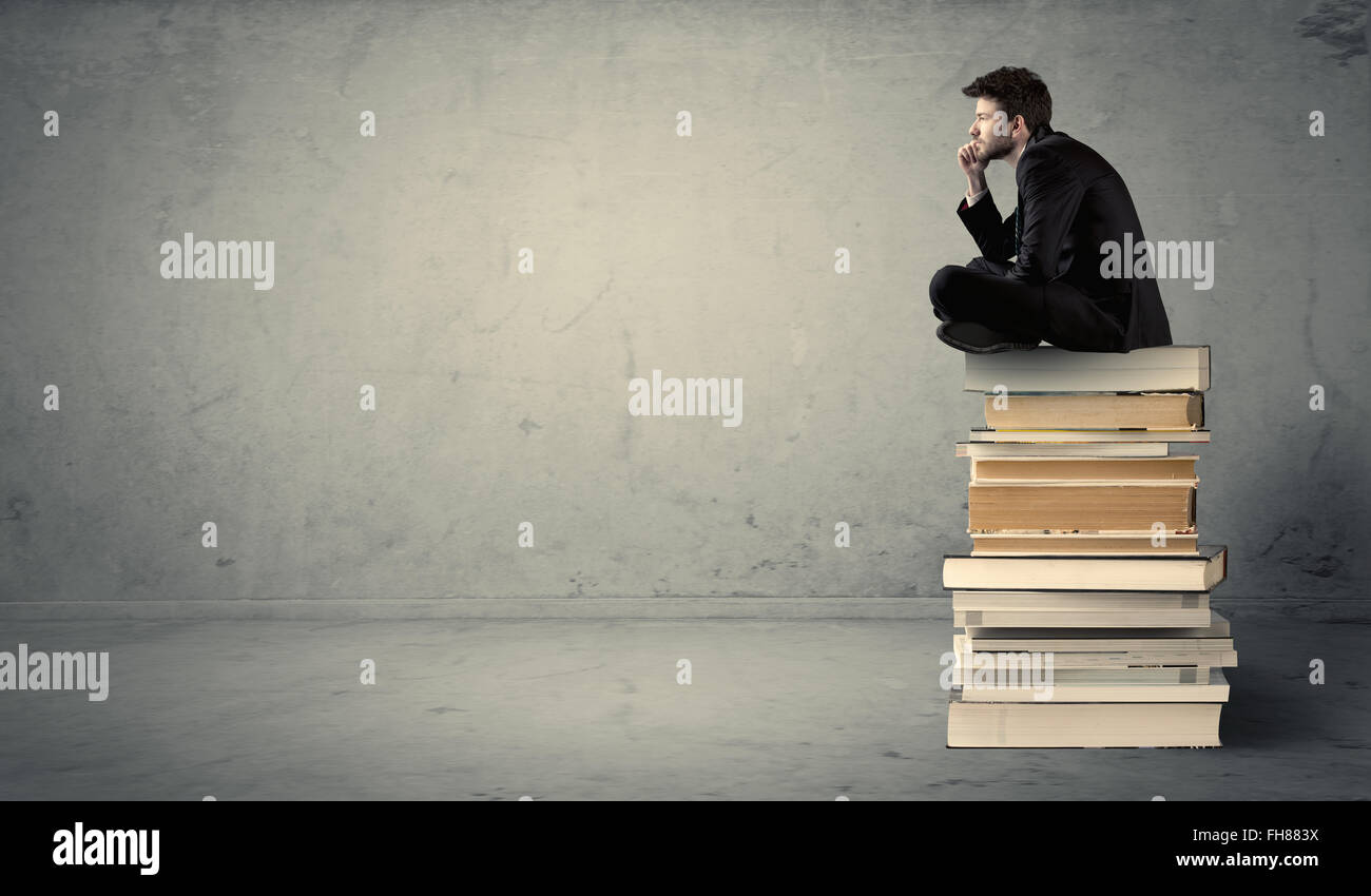Student sitting on stack of books Stock Photo - Alamy