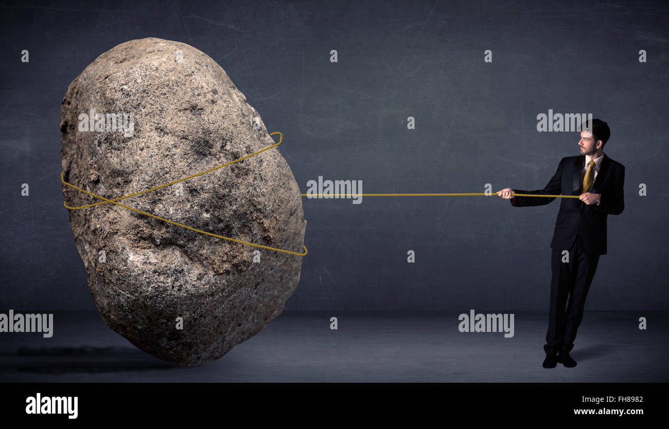 Businessman pulling huge rock with a rope Stock Photo - Alamy
