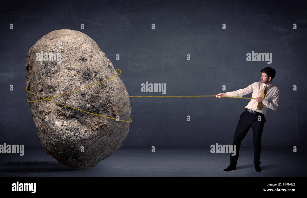 Businessman pulling huge rock with a rope Stock Photo - Alamy
