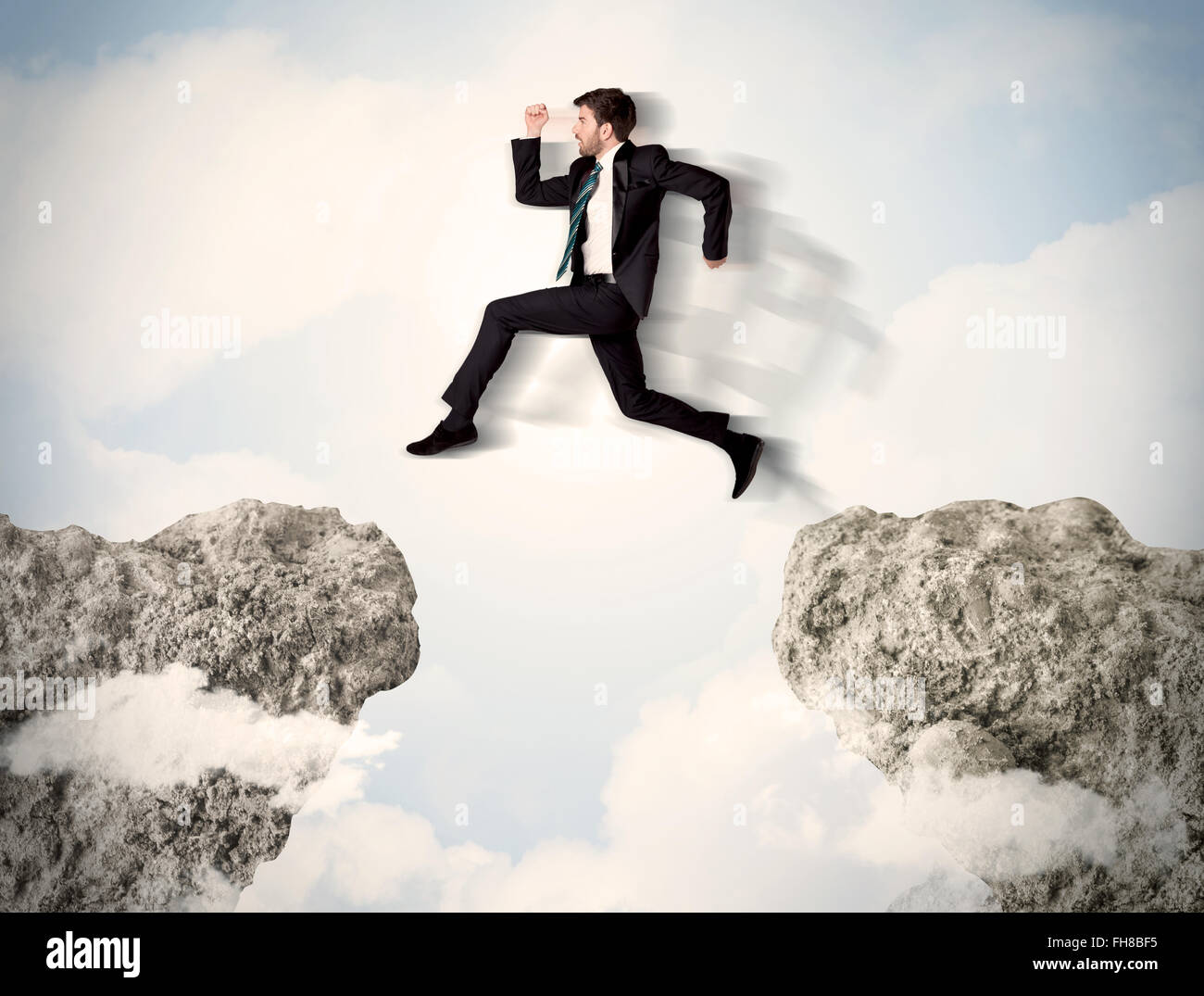 Happy business man jumping over a cliff Stock Photo - Alamy