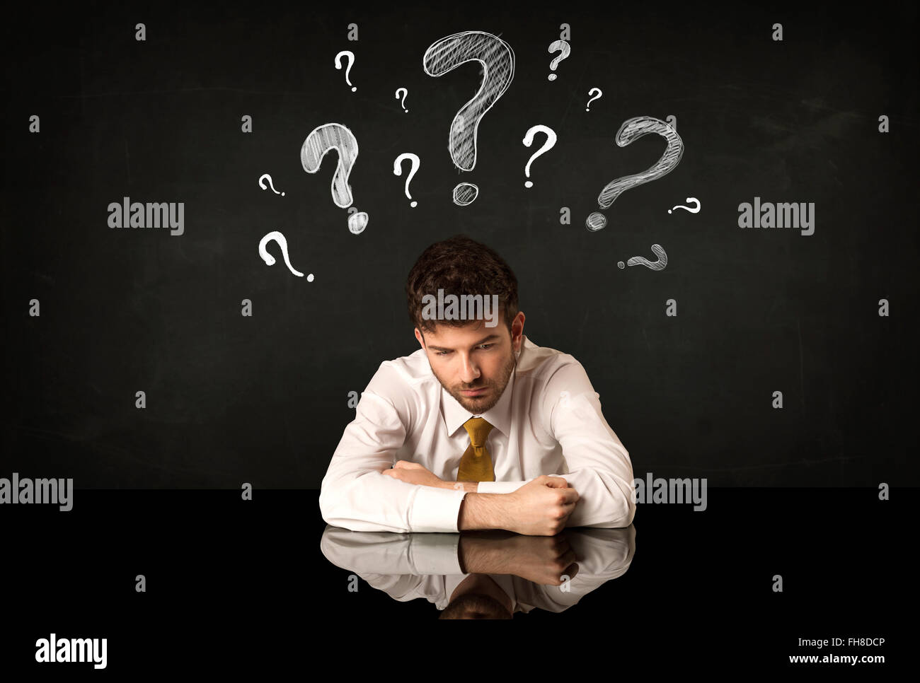 Sitting businessman under question marks Stock Photo - Alamy