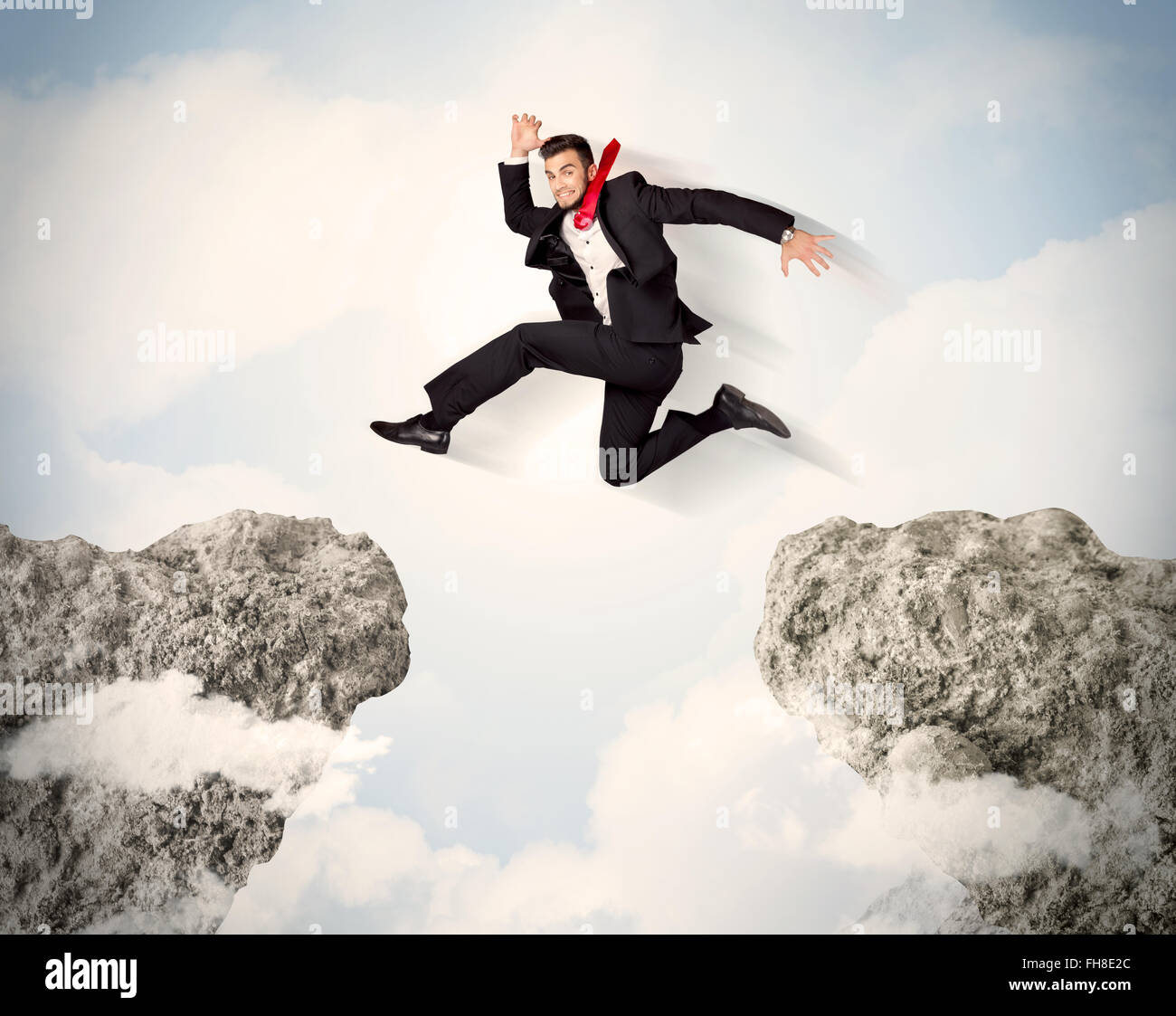 Happy business man jumping over a cliff Stock Photo - Alamy