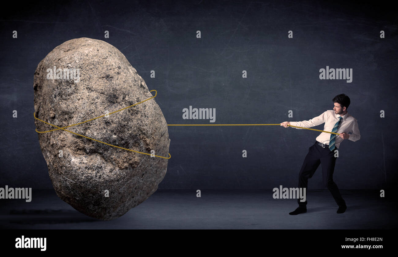 Businessman pulling huge rock with a rope Stock Photo - Alamy