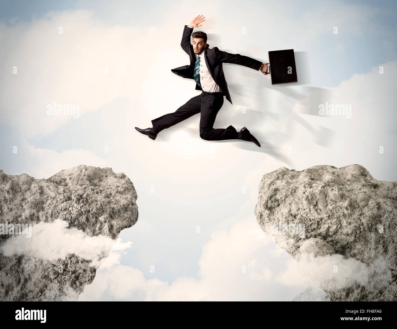 Happy business man jumping over a cliff Stock Photo - Alamy