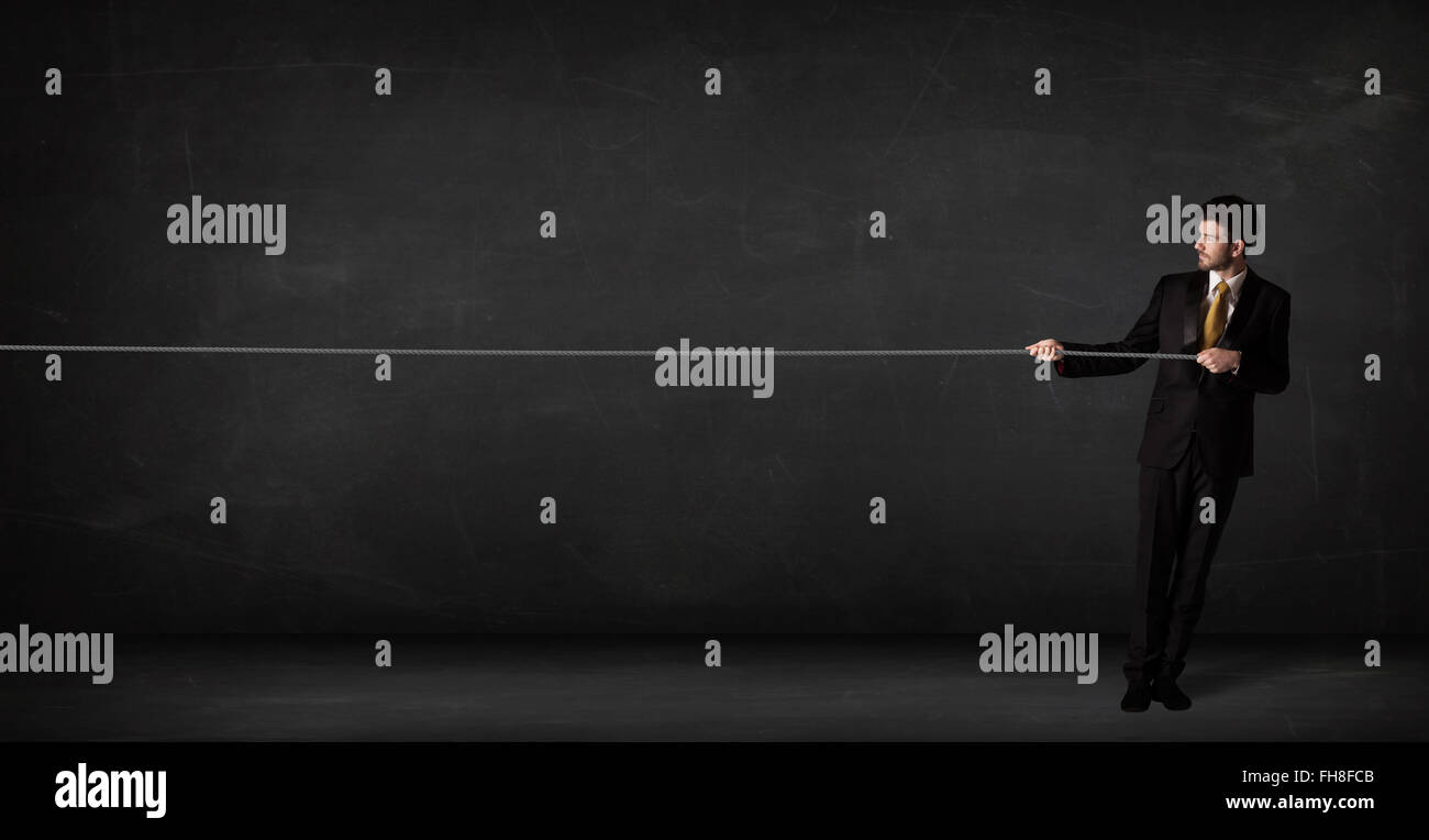 Businessman pulling rope on grey background Stock Photo - Alamy