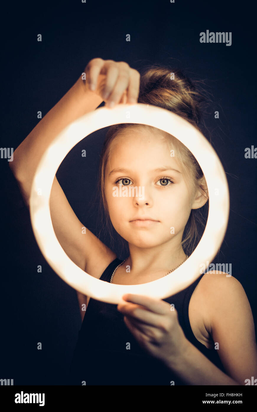 Beautiful young girl gymnast holding a glowing circle Stock Photo - Alamy