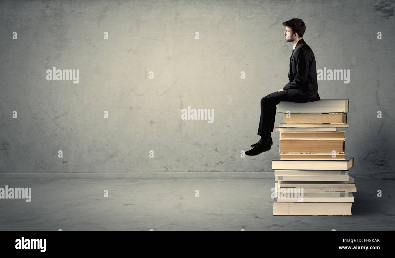 Student sitting on stack of books Stock Photo - Alamy