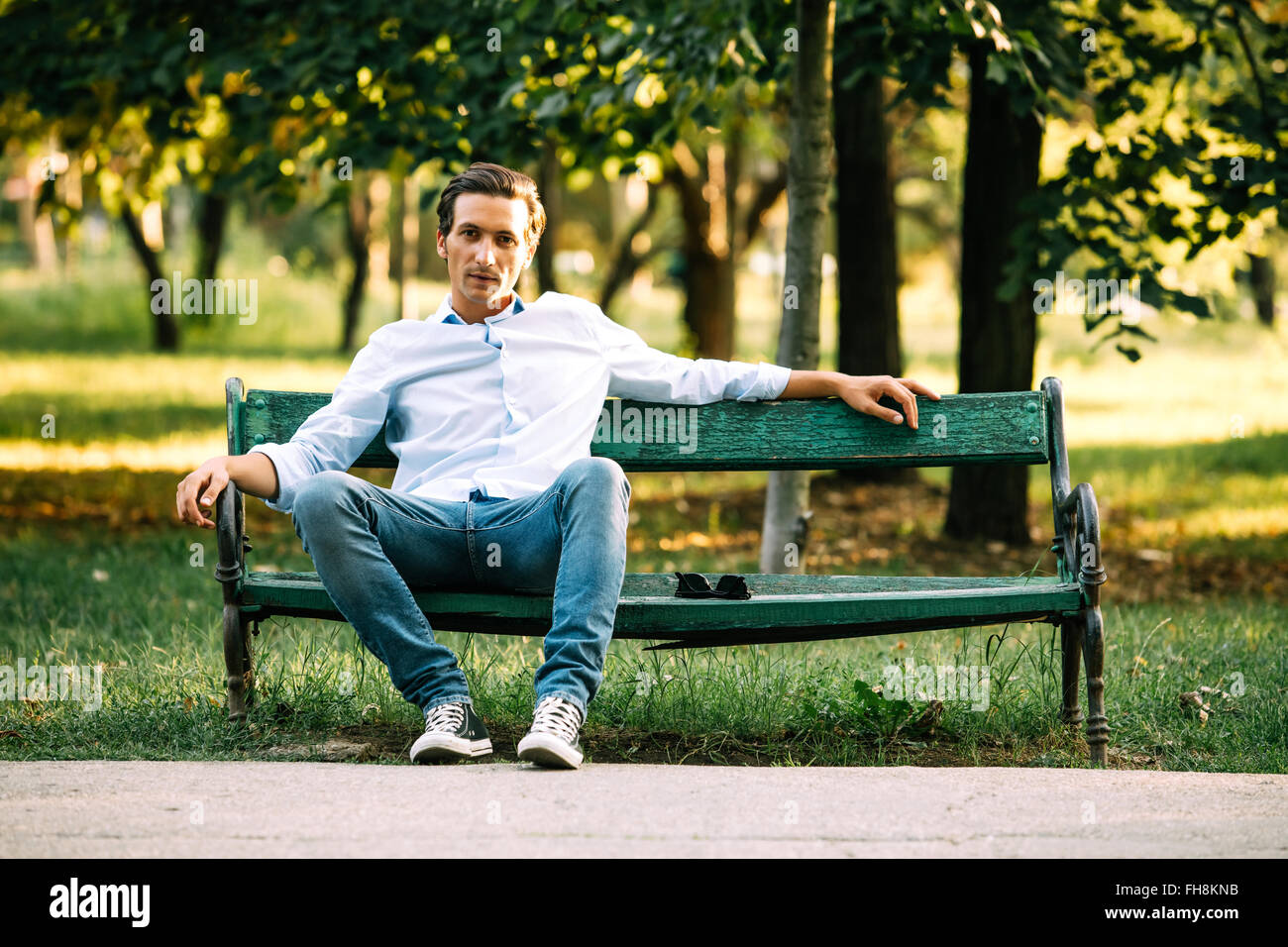 atractive adult man sitting alone on bench in park Stock Photo - Alamy
