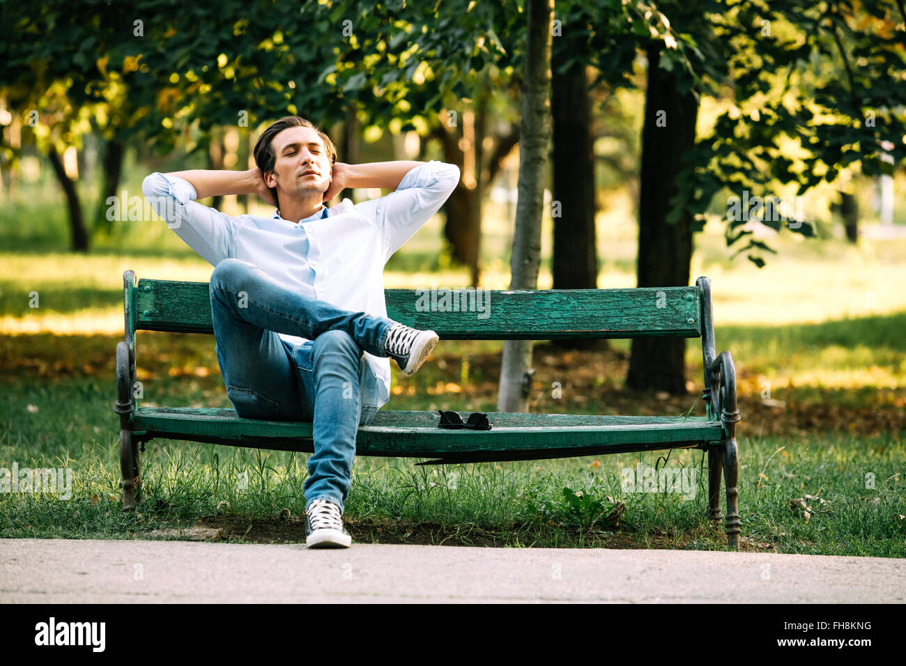 atractive adult man sitting alone on bench in park Stock Photo - Alamy