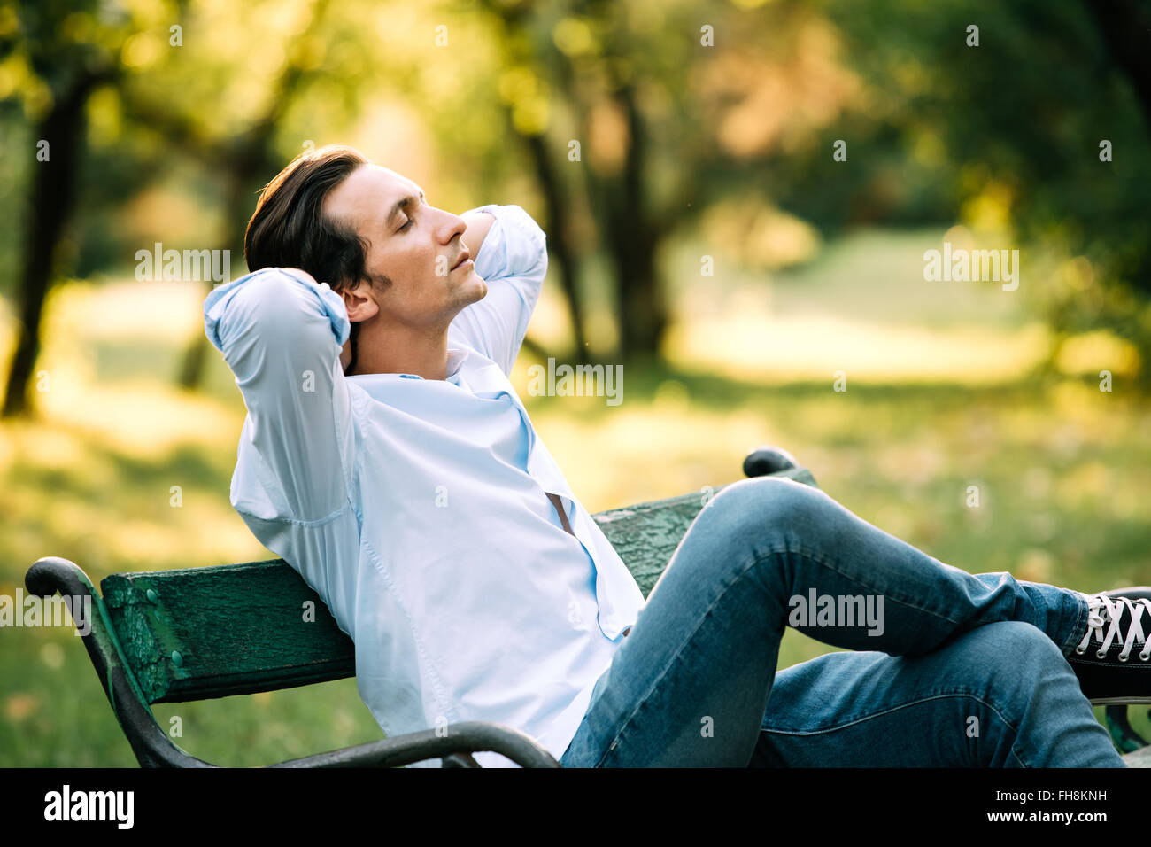 atractive adult man sitting alone on bench in park Stock Photo - Alamy