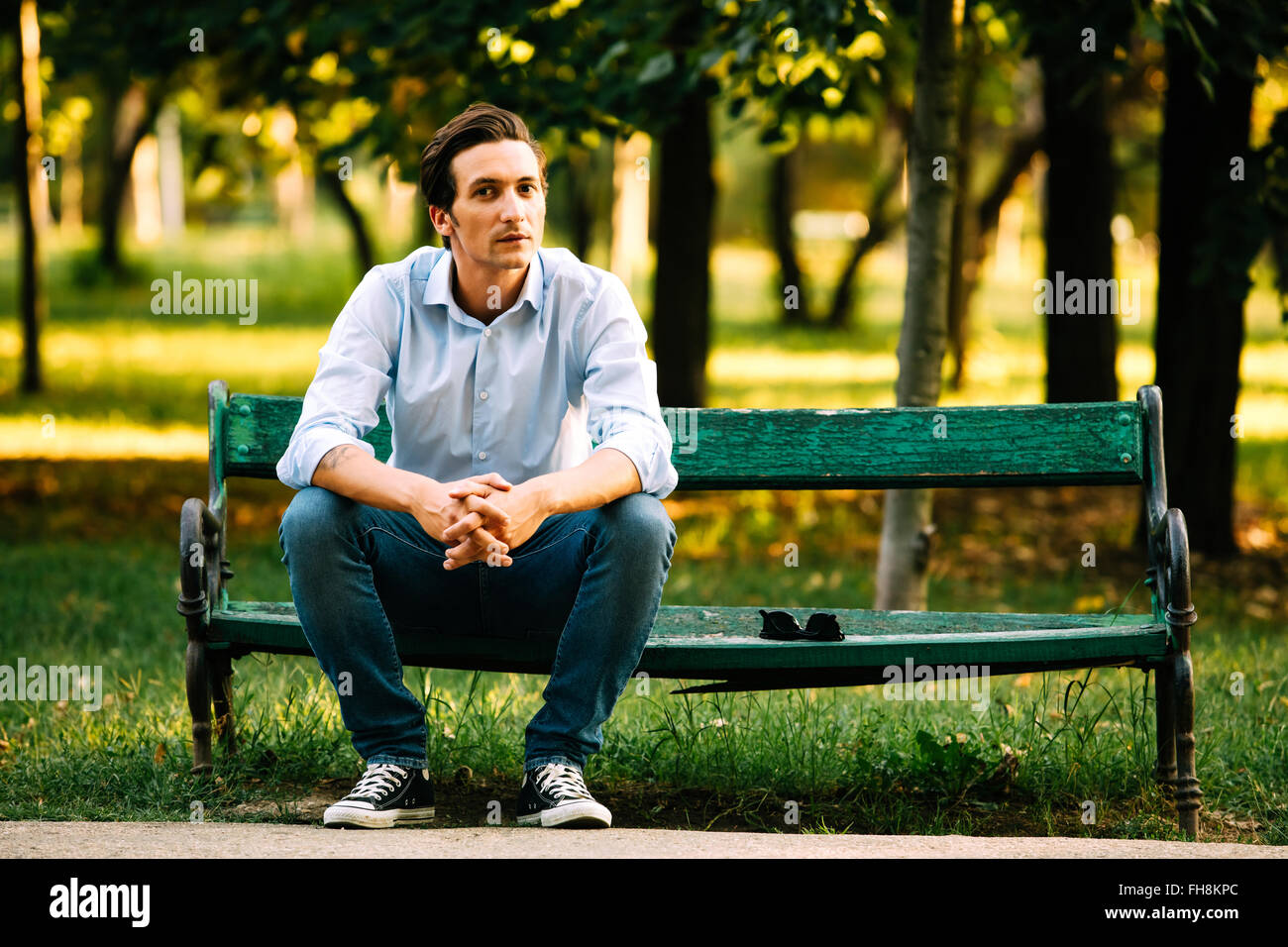 atractive adult man sitting alone on bench in park Stock Photo - Alamy