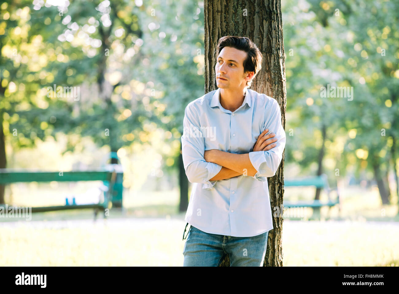 Handsome young man leaning against tree hi-res stock photography and ...