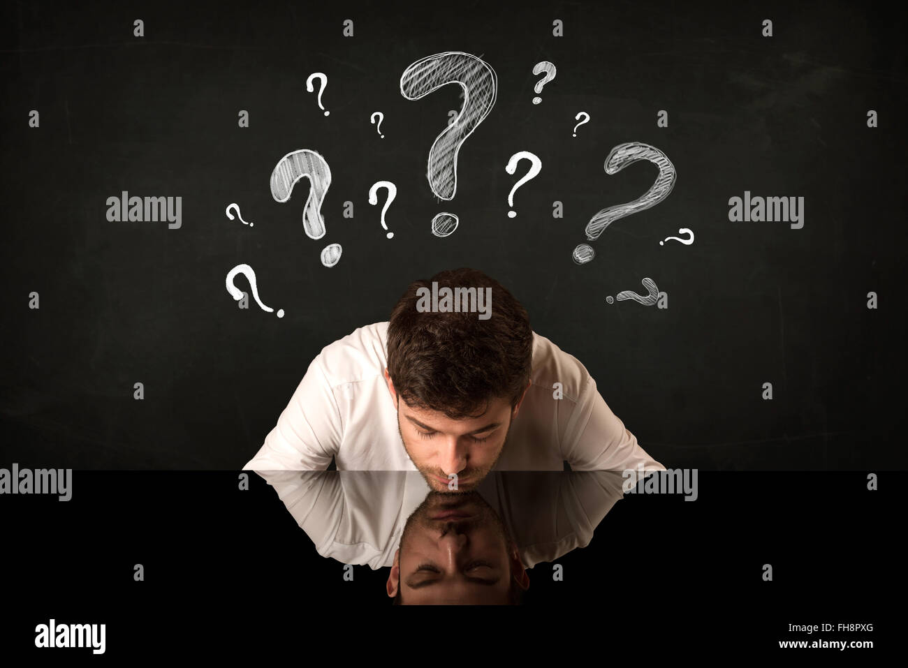 Sitting businessman under question marks Stock Photo - Alamy