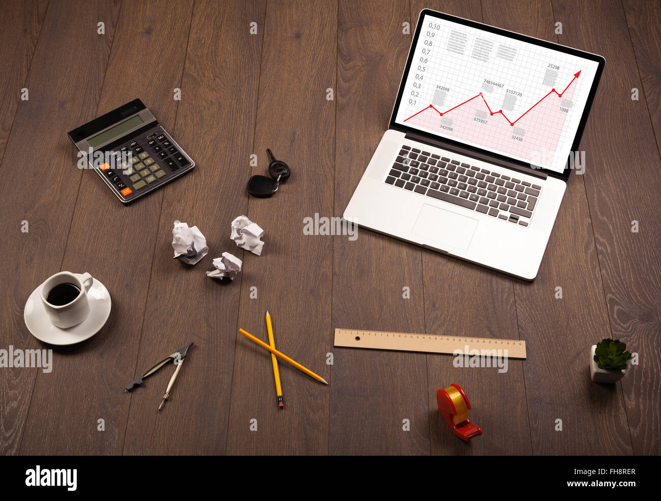 Computer desk with laptop and red arrow chart in screen Stock Photo - Alamy
