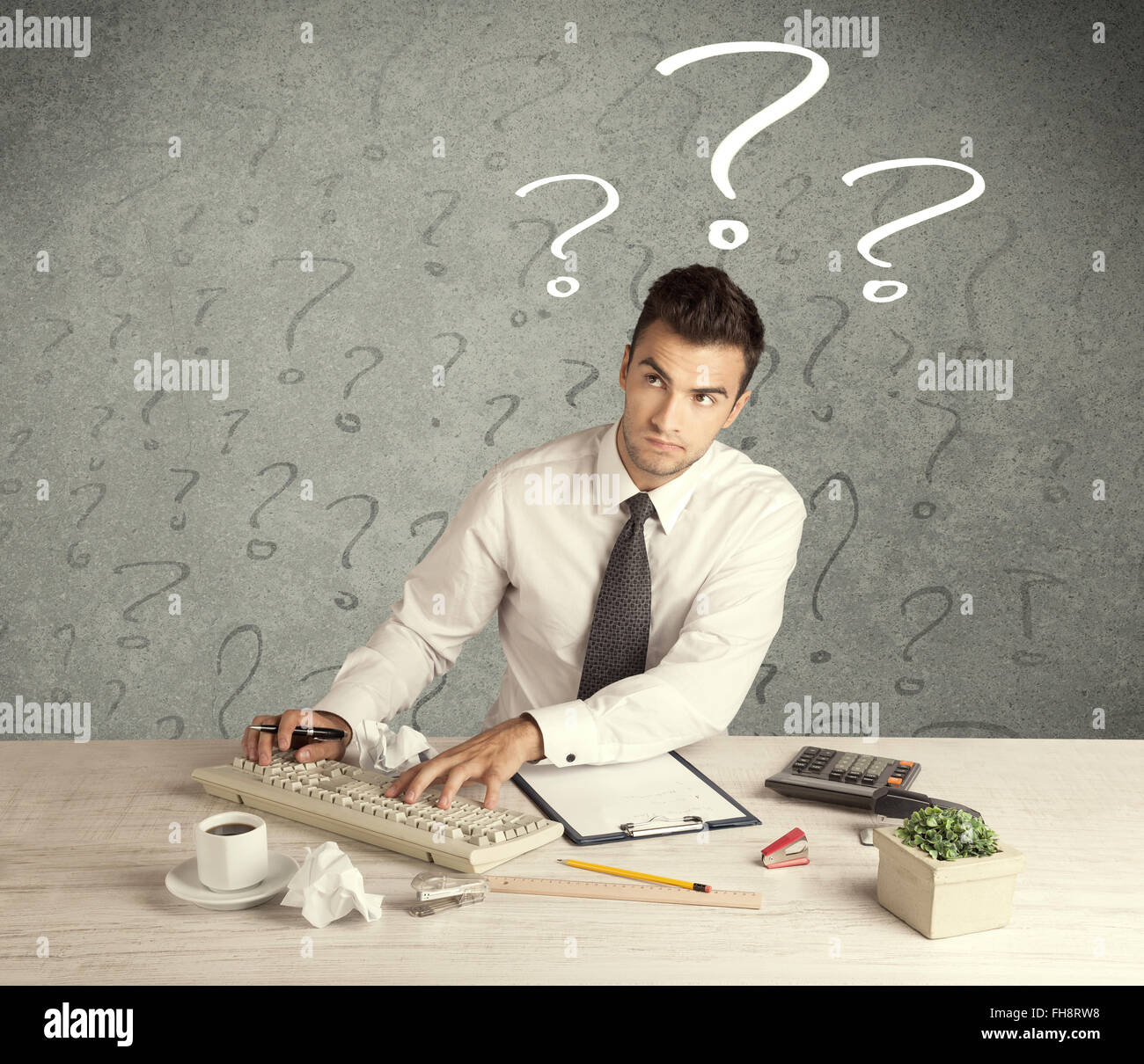 Businessman at desk with question mark Stock Photo - Alamy