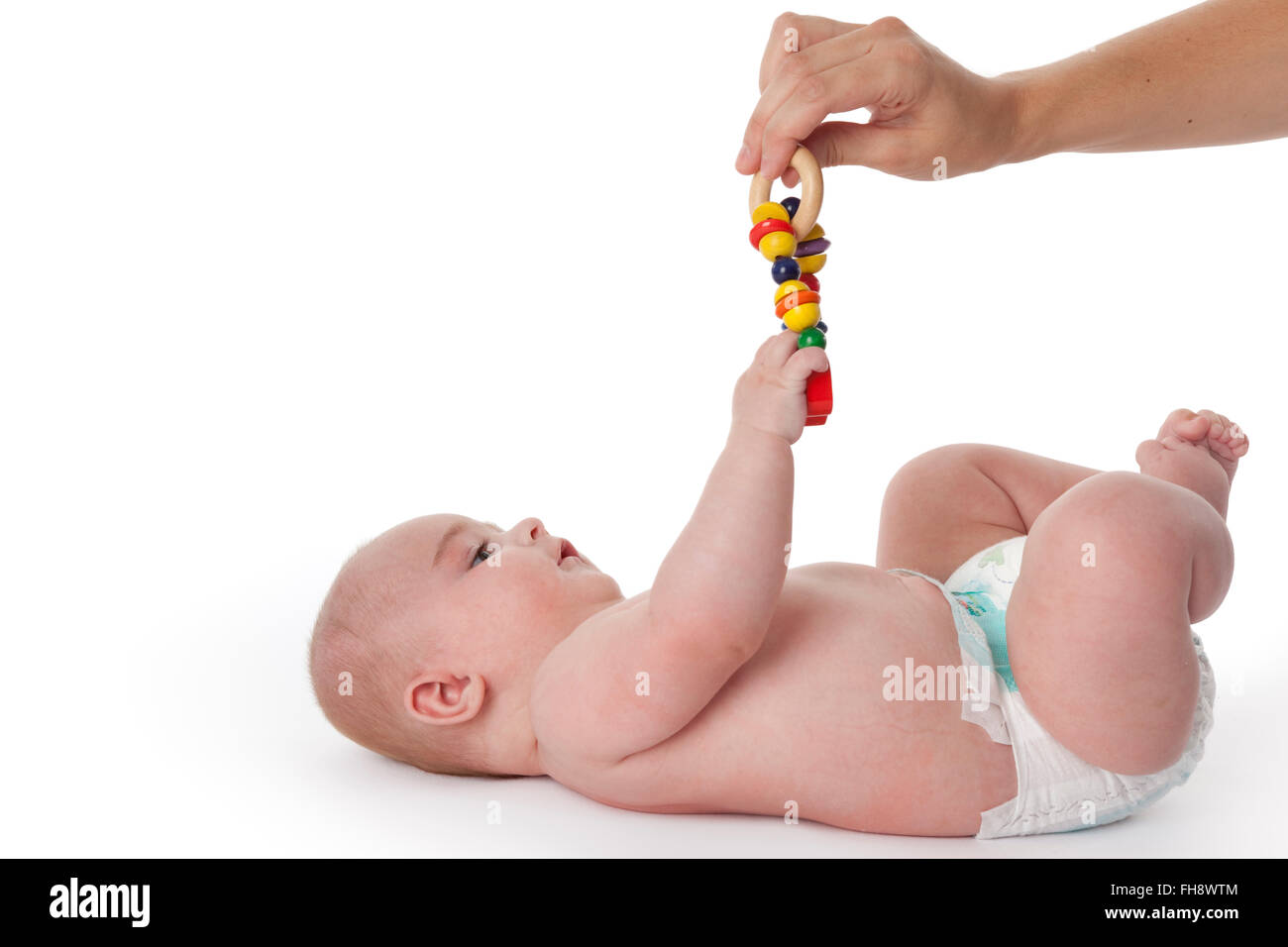 Baby boy looking reaching for a colored toy on white background with ...
