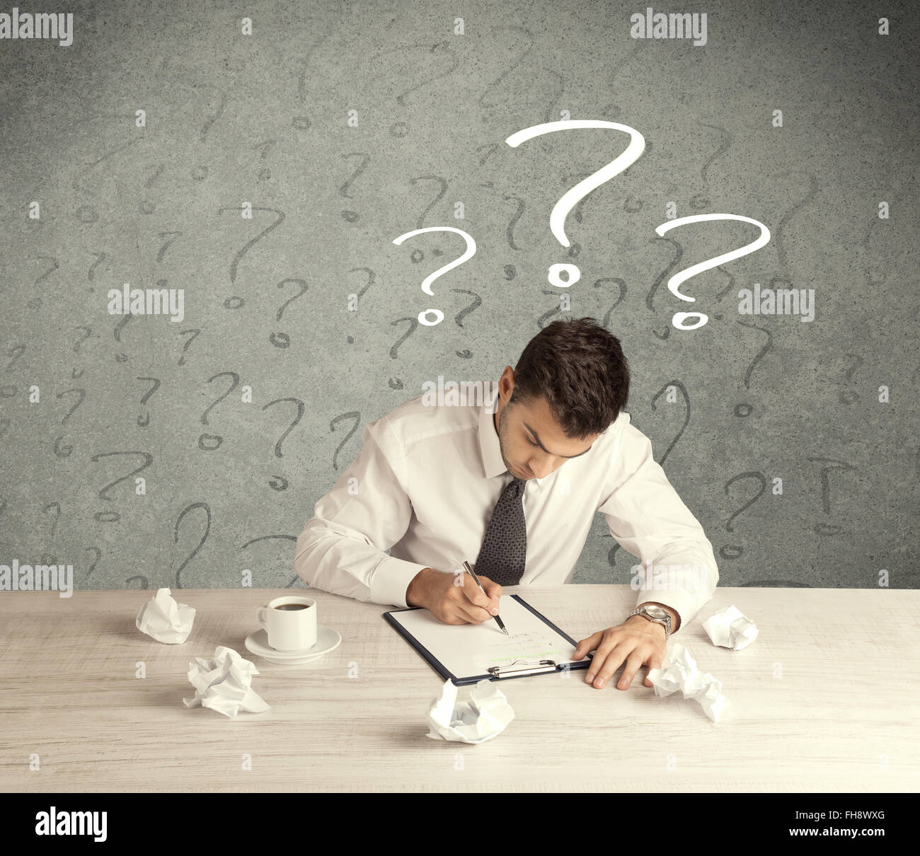 Businessman at desk with question mark Stock Photo - Alamy