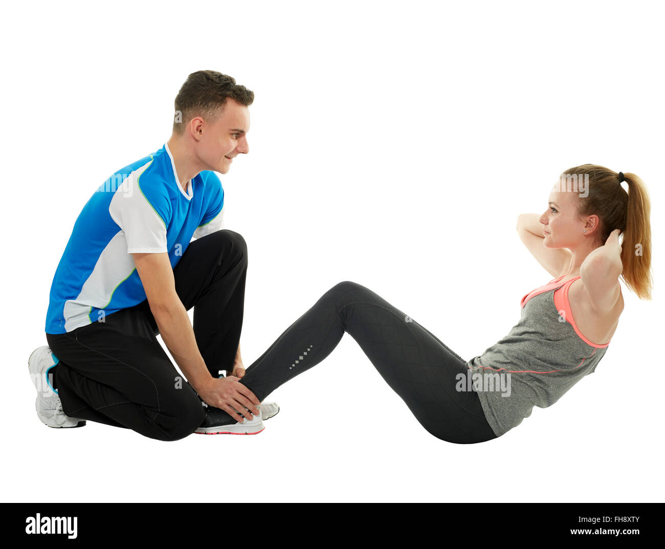 Teenagers boy and girl helping each other to do abs crunches Stock ...