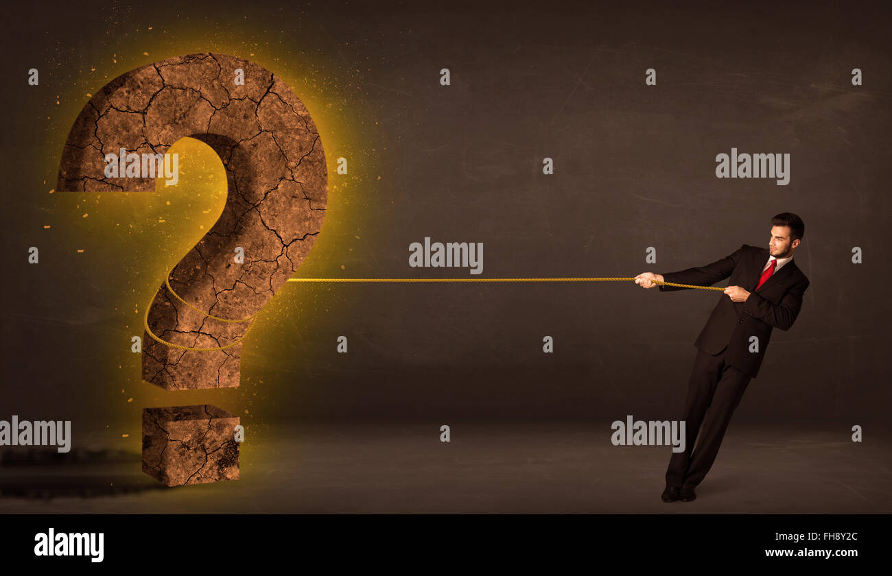 Business man pulling a big solid question mark stone Stock Photo - Alamy