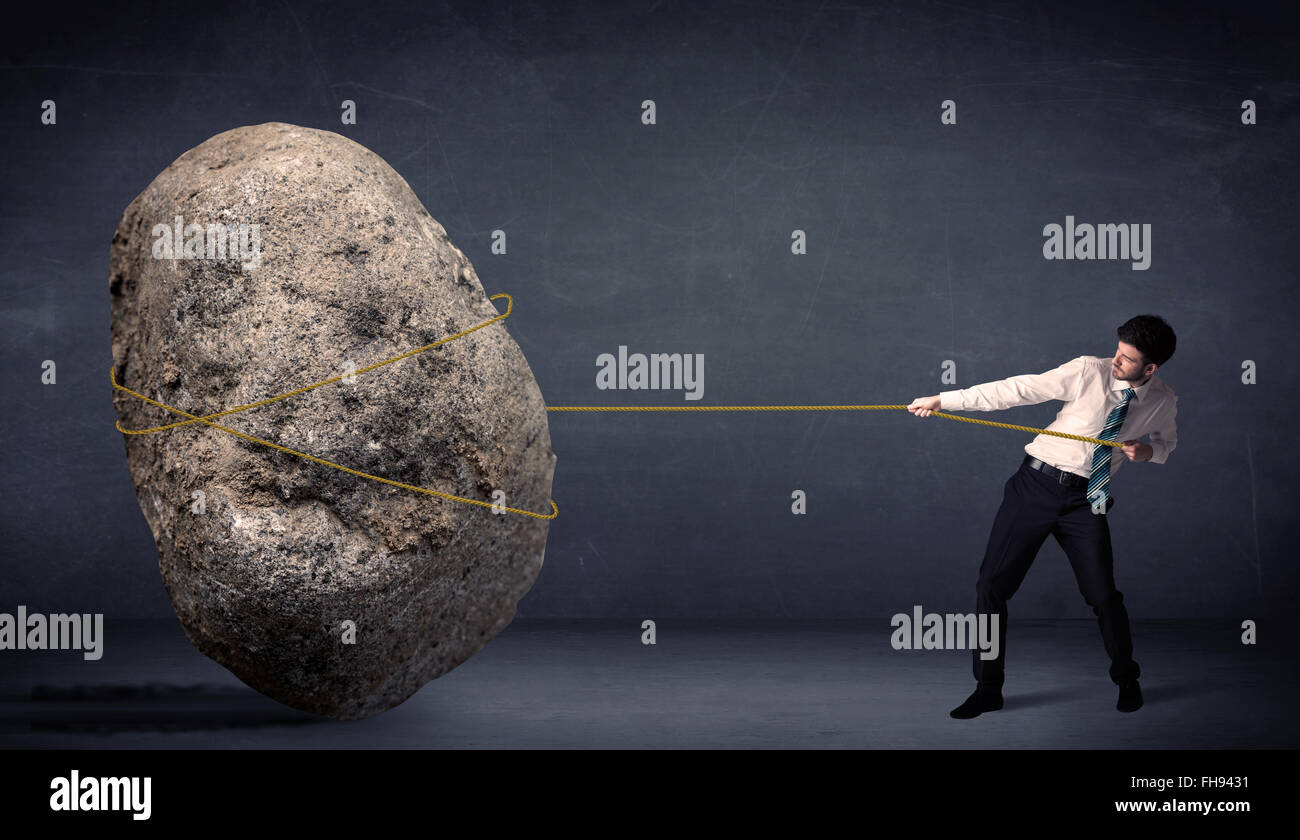 Businessman pulling huge rock with a rope Stock Photo - Alamy