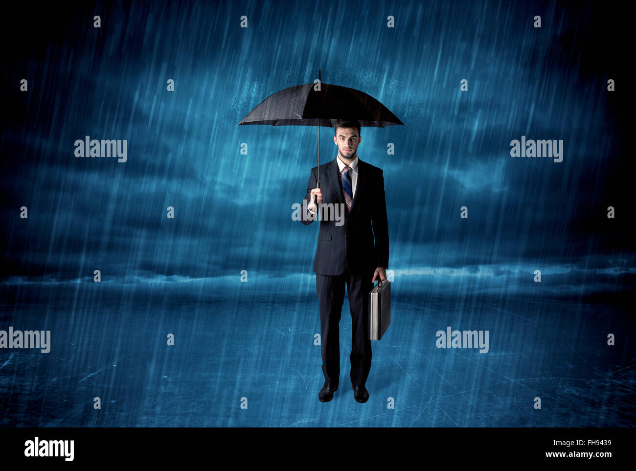 Business man standing in rain with an umbrella Stock Photo - Alamy
