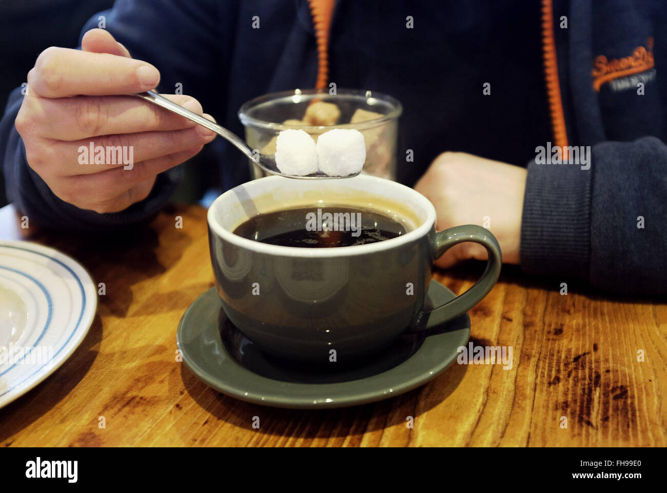Stirring sugar cubes into a cup of black coffee Stock Photo - Alamy