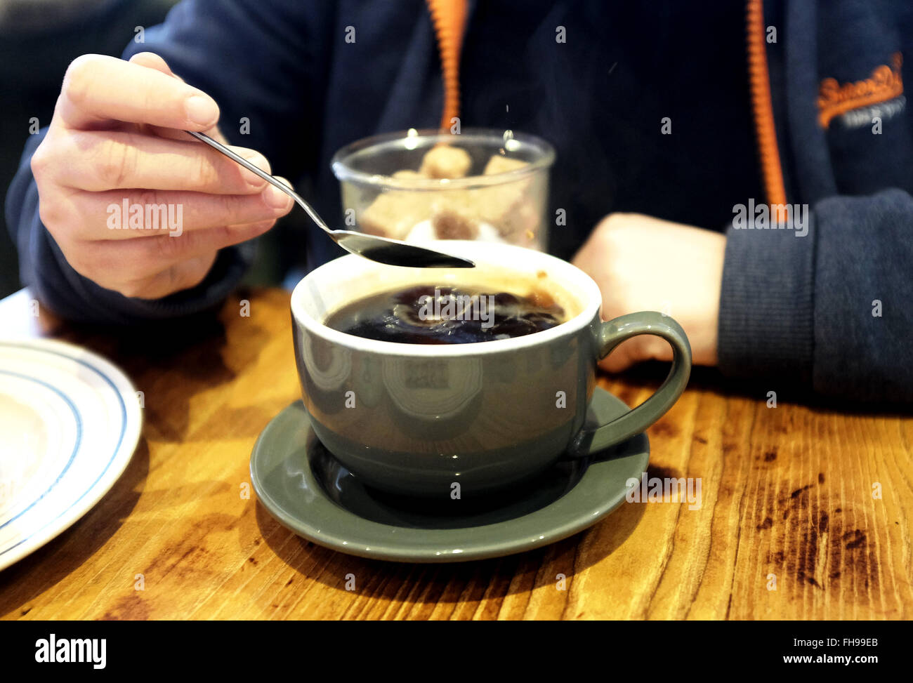 Stirring sugar cubes into a cup of black coffee Stock Photo - Alamy