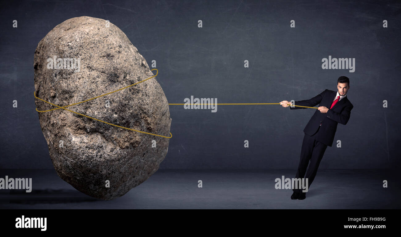 Businessman pulling huge rock with a rope Stock Photo - Alamy