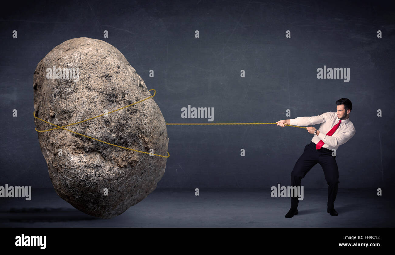 Businessman pulling huge rock with a rope Stock Photo - Alamy
