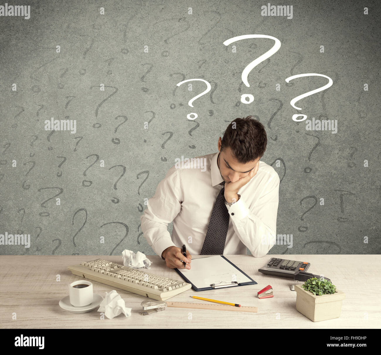 Businessman at desk with question mark Stock Photo - Alamy