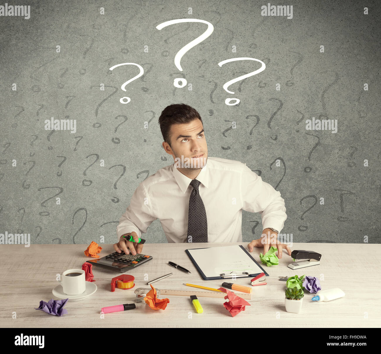 Businessman at desk with question mark Stock Photo - Alamy