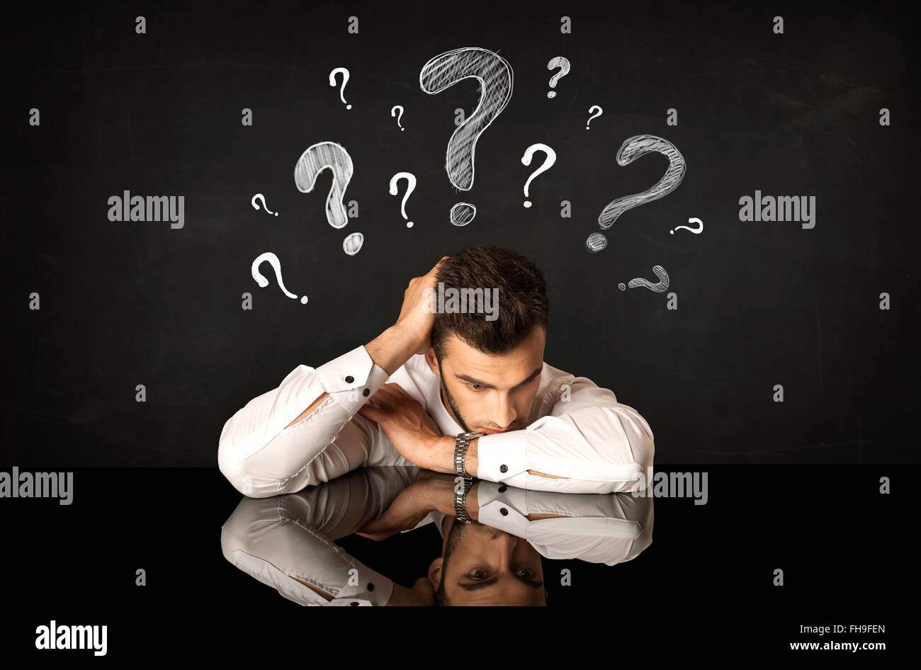 Sitting businessman under question marks Stock Photo - Alamy