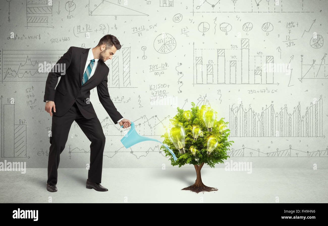 Business man pouring water on lightbulb growing tree Stock Photo - Alamy
