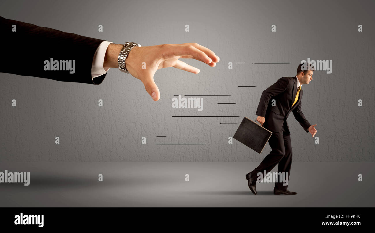 Businessman running away from a huge hand Stock Photo - Alamy