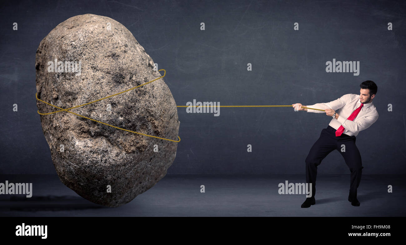 Businessman pulling huge rock with a rope Stock Photo - Alamy