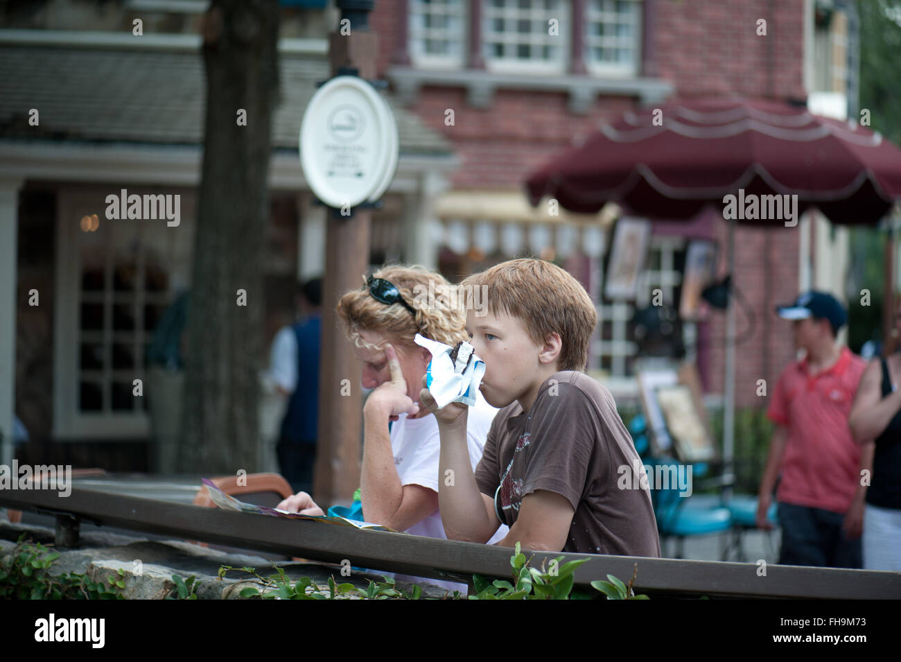 Young kids having fun eating trash food at the amusement park of Disney ...