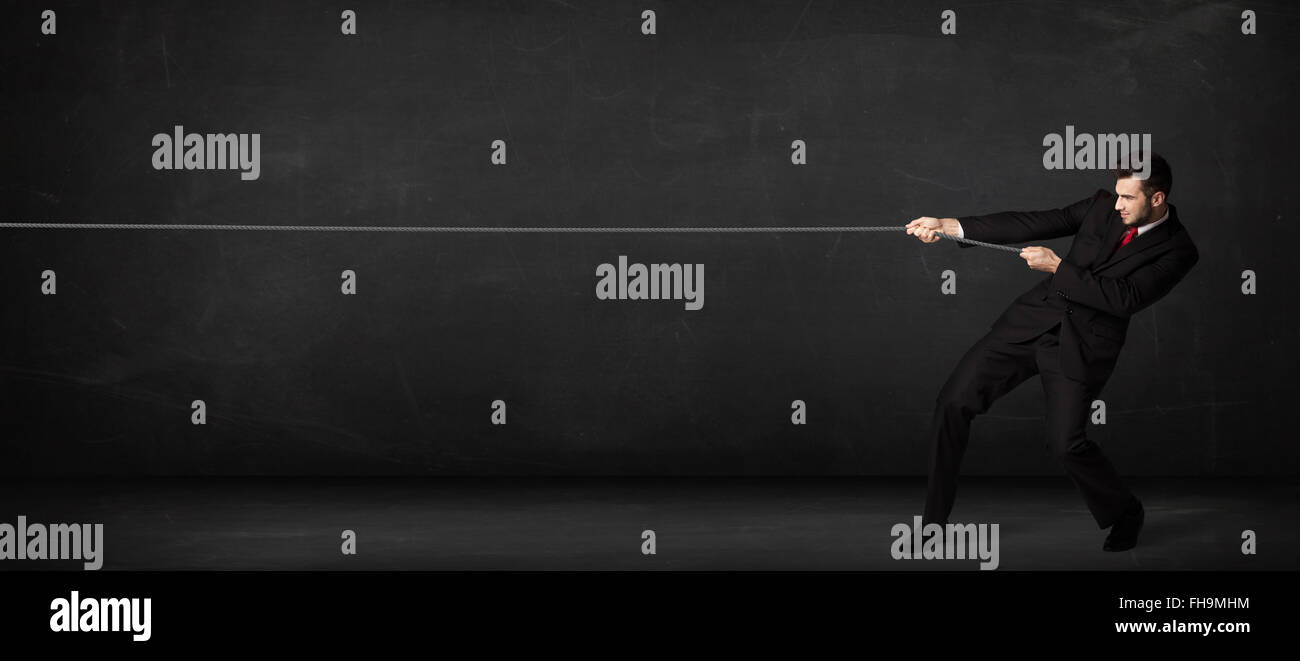 Businessman pulling rope on grey background Stock Photo - Alamy