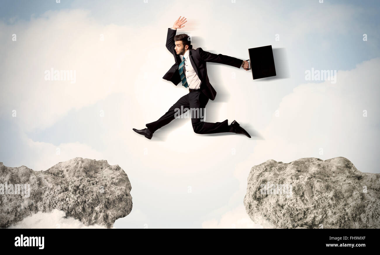 Happy business man jumping over a cliff Stock Photo - Alamy