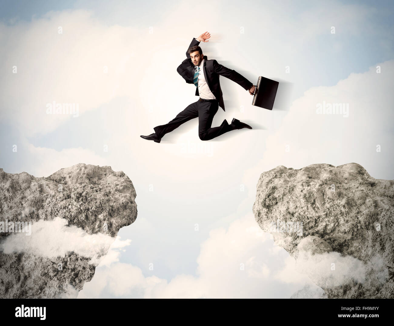 Happy business man jumping over a cliff Stock Photo - Alamy