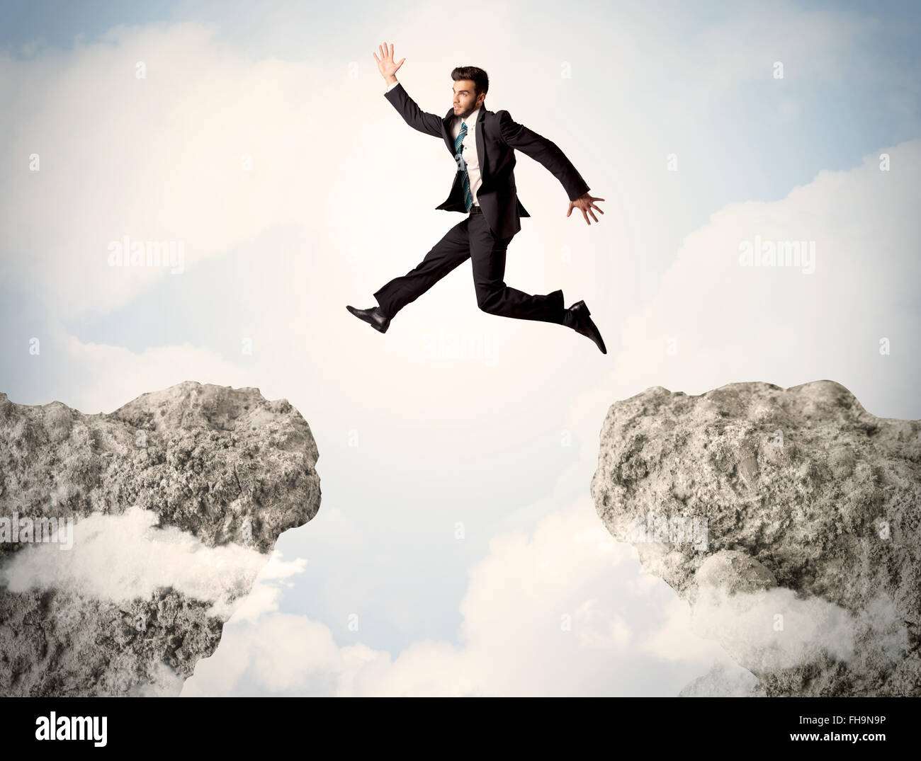Happy business man jumping over a cliff Stock Photo - Alamy