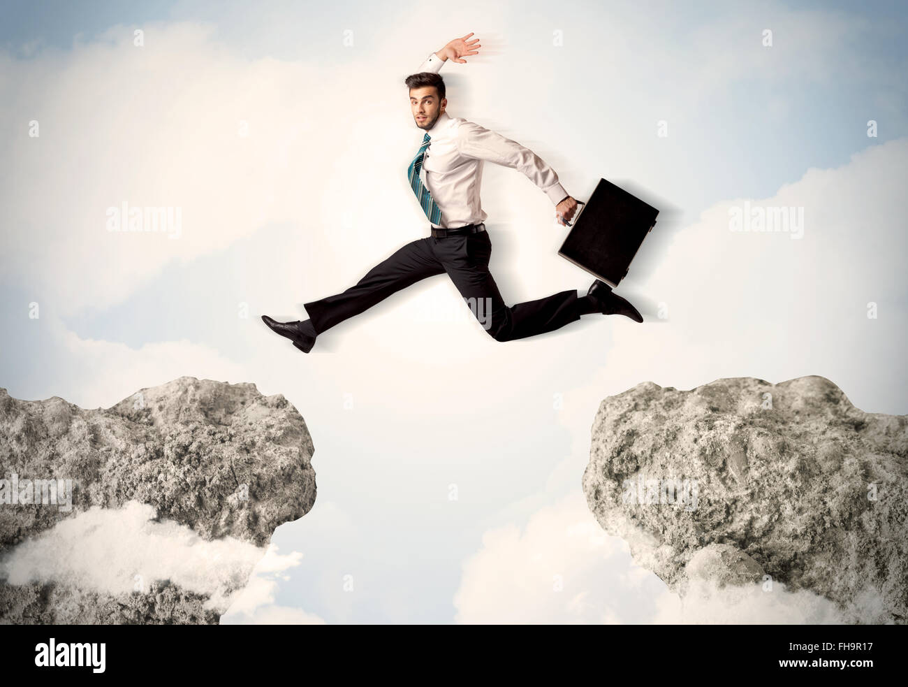 Happy business man jumping over a cliff Stock Photo - Alamy