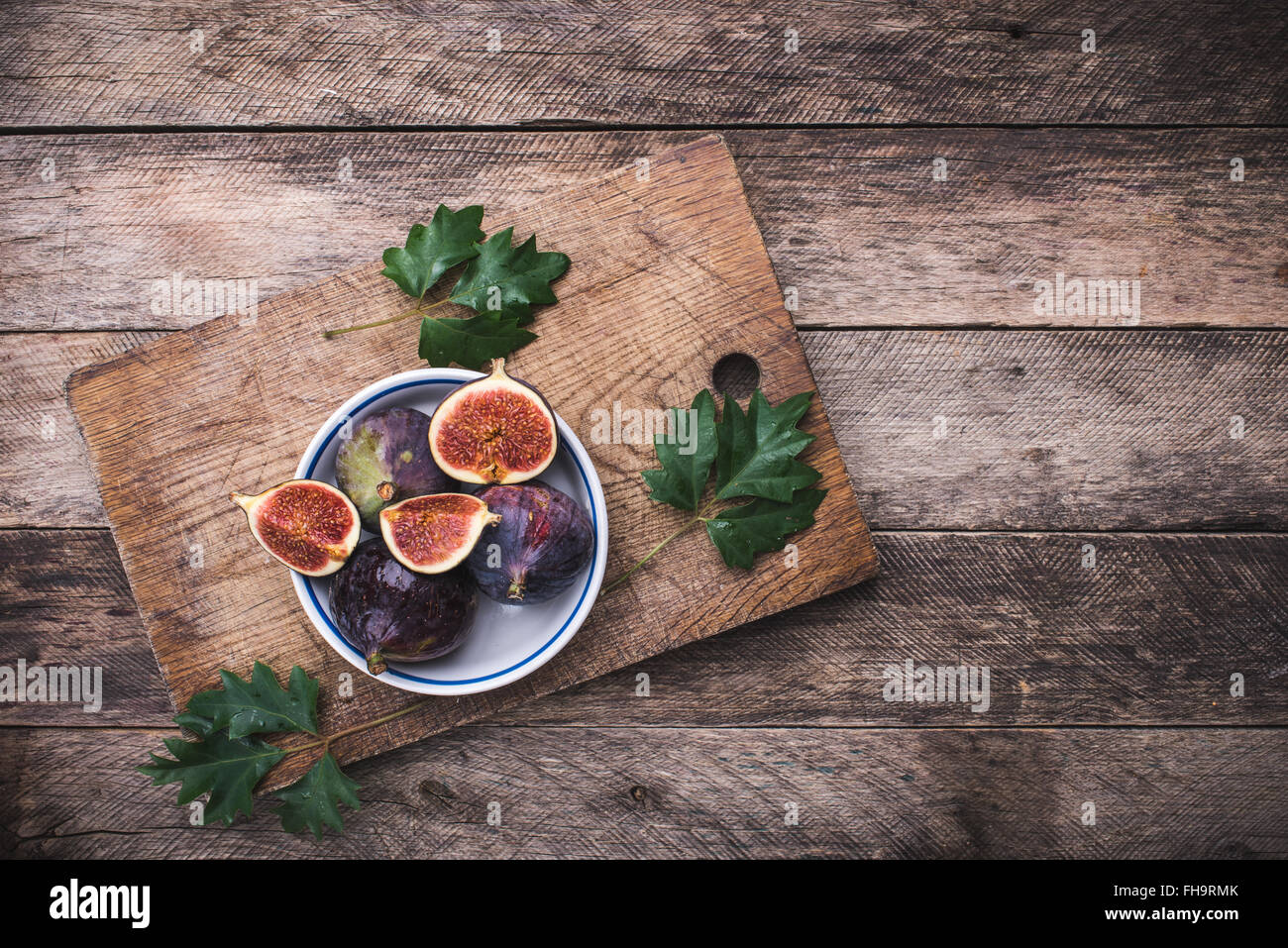 rustic style Cut figs in flat dish on choppingboard. Autumn season food ...